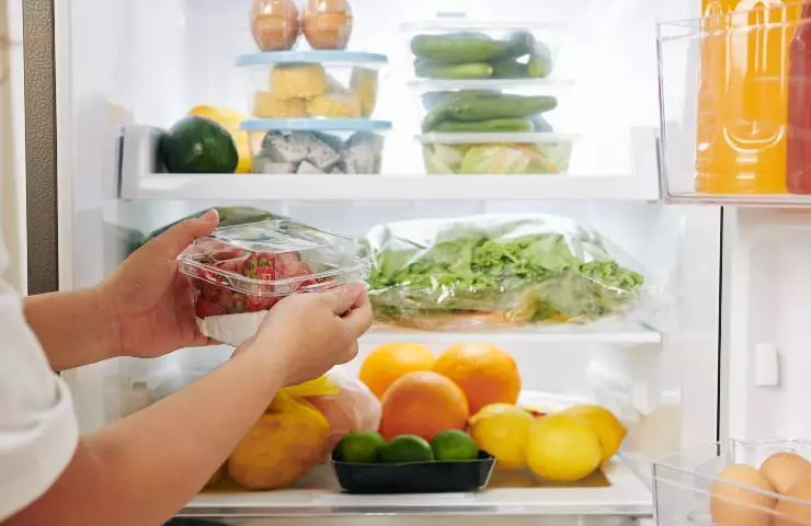 O femeie pune mâncare în frigider