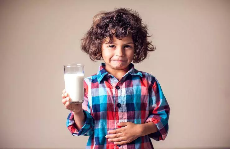 Baby with glass of milk in hand
