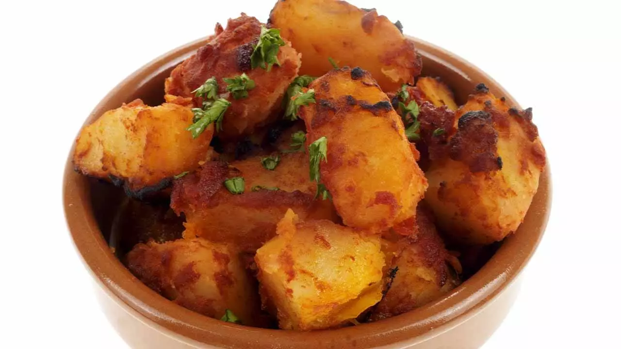 Uncooked uncooked potatoes in the oven with spices and tomato