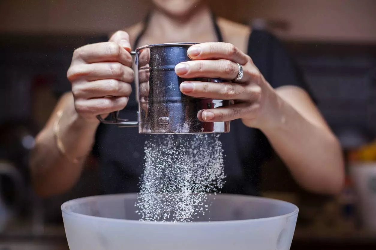 Closeup on a woman sifting falling flour